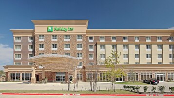 Um hotel Holiday Inn com fachada de tijolos, várias janelas e entrada coberta.