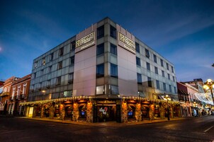 Um hotel de vários andares com fachada moderna, exibindo a sinalização 'Cámara de Tradición' e 'El Antaño Rojo'.