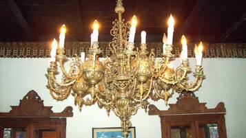 Um candelabro com várias velas, um quadro emoldurado de um edifício, e armários de madeira com portas de vidro.