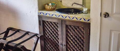 Um banheiro compacto com uma pia pequena, uma toalha pendurada na parede e um painel de azulejos decorativo.