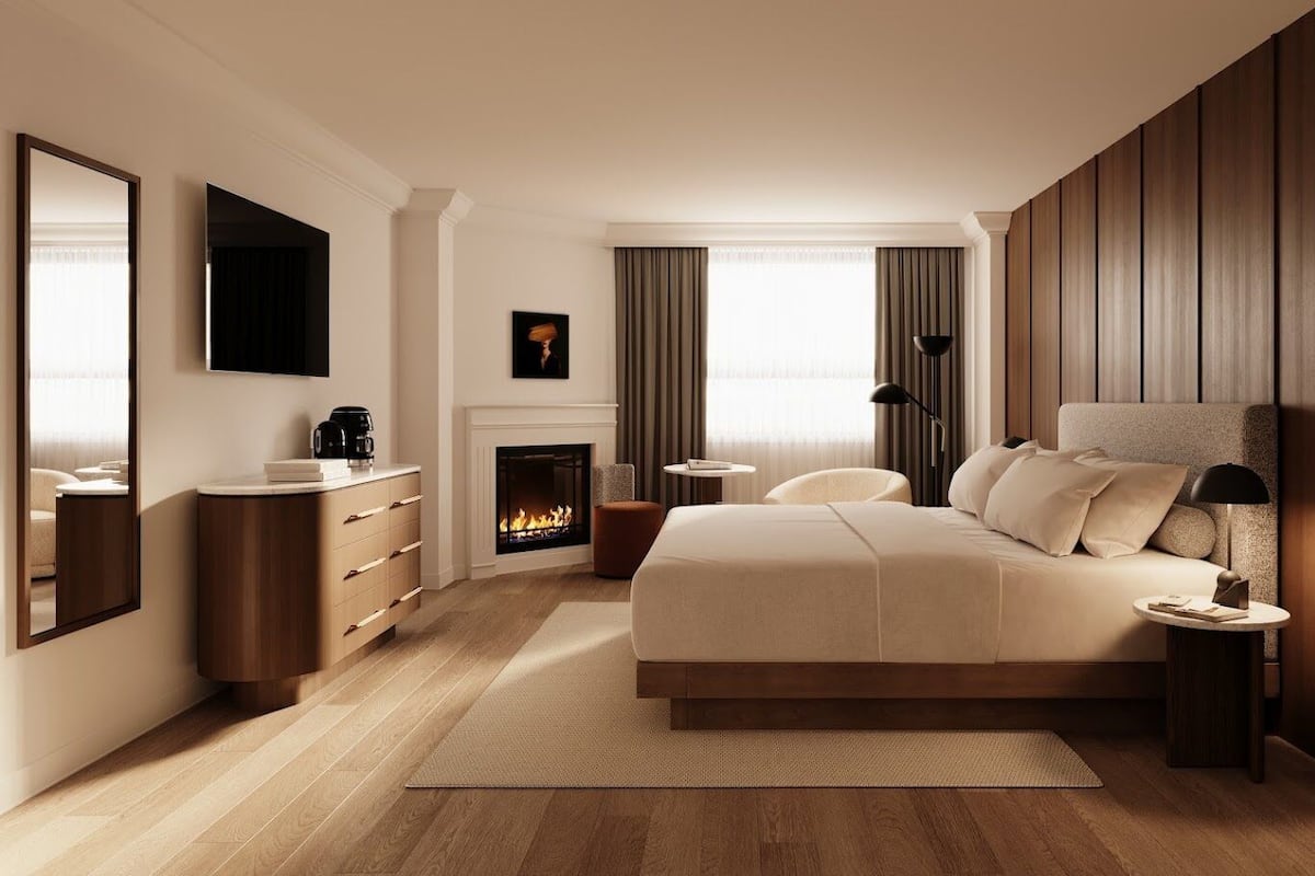 Quarto moderno com uma cama grande, lareira, mesa de cabeceira, espelho e guarda-roupa.