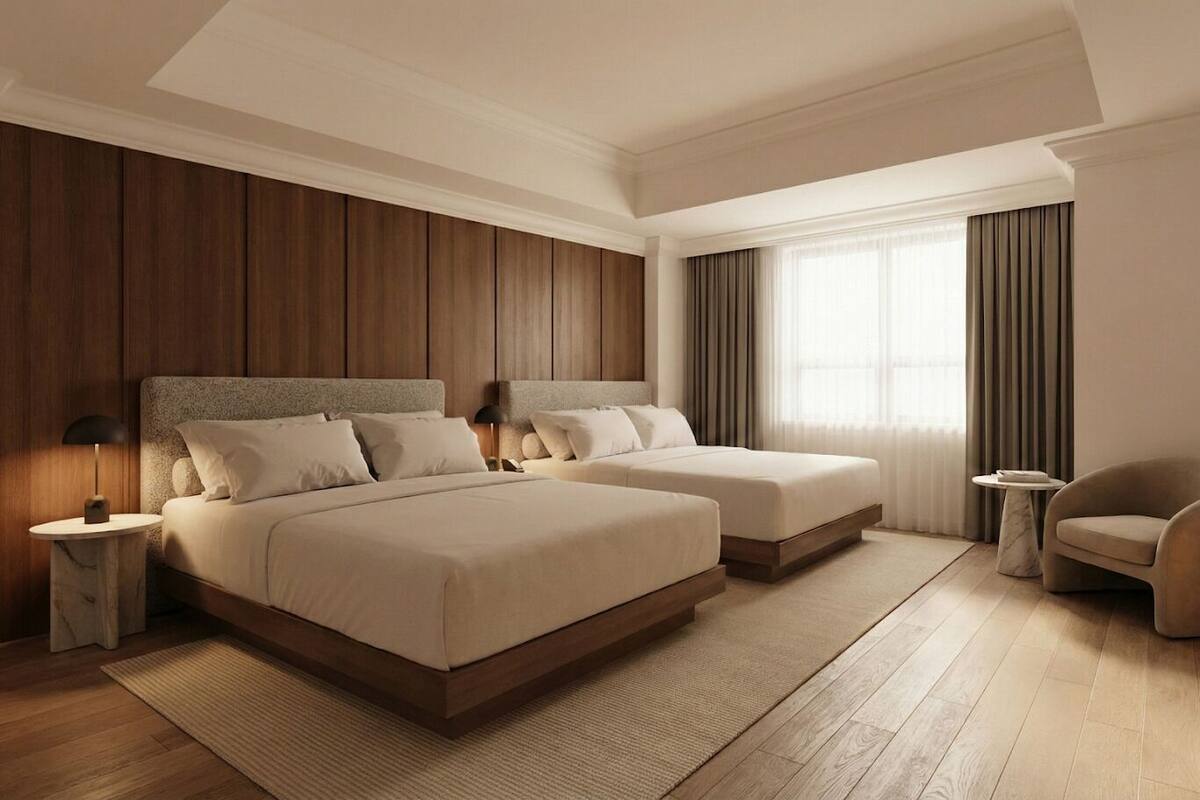 Quarto de hotel moderno com duas camas, um espaço de estar e uma janela grande com cortinas.
