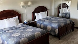 Quarto de hotel com duas camas de madeira, um ventilador de teto e um espelho grande.