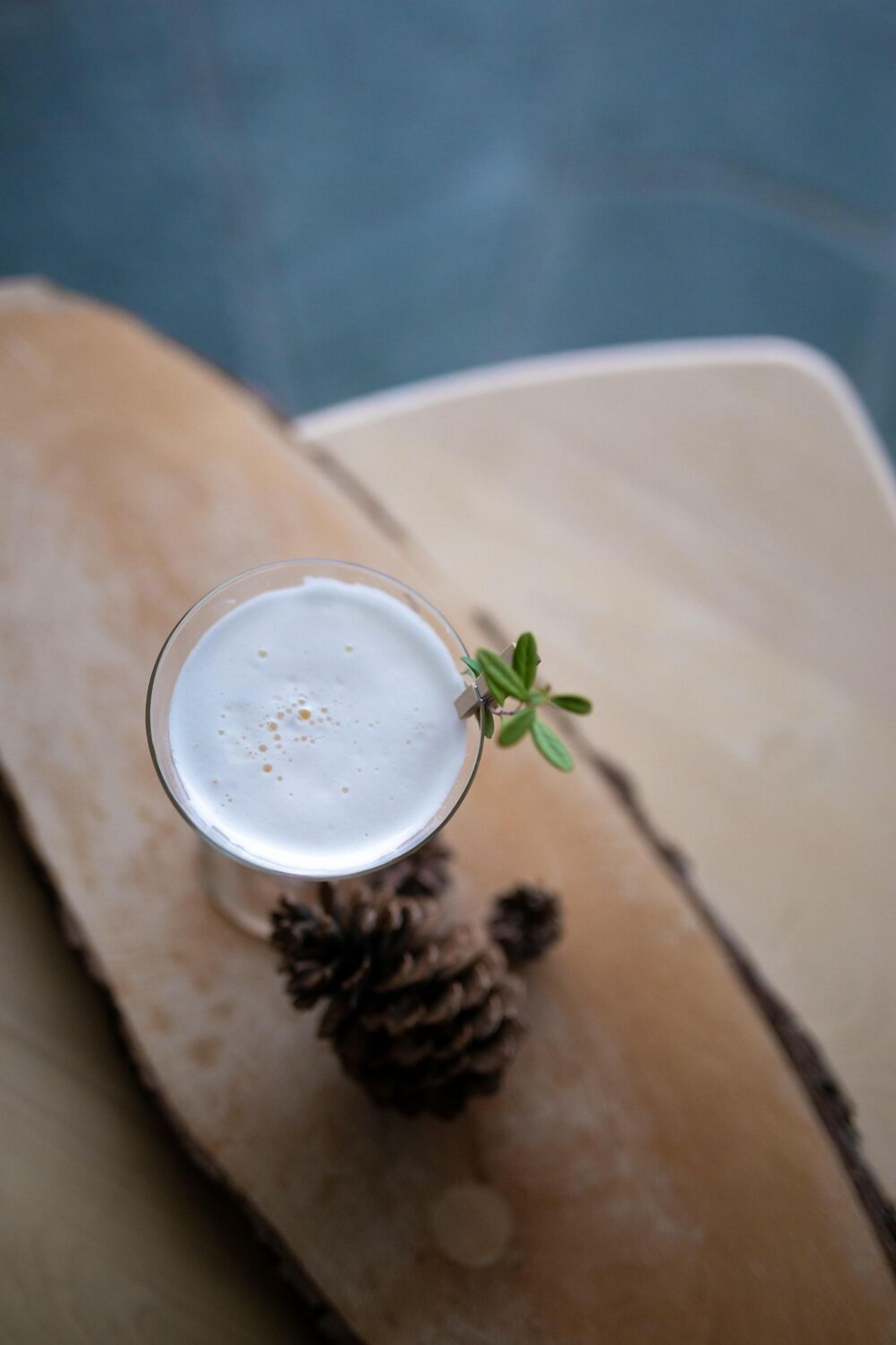 Um copo de bebida branca com um enfeite sobre uma superfície de madeira.
