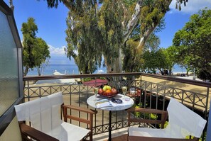 Varanda com mesa posta para dois, com vista para uma praia com guarda-sóis e o mar.
