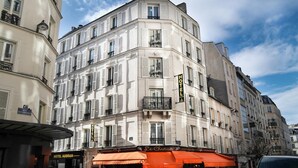 Um edifício de vários andares na esquina, com sacadas e janelas amplas.