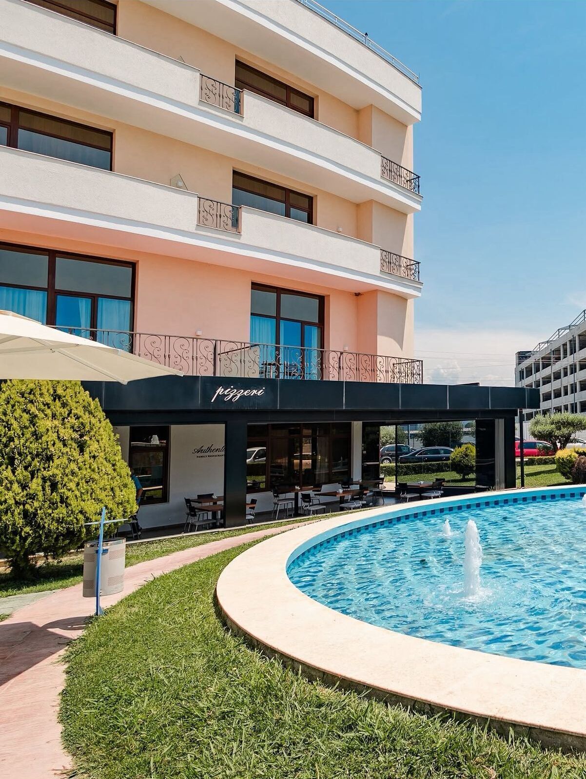 Um hotel com piscina, área de estar externa e um restaurante chamado 'pizzeria'.