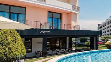Um hotel com piscina, área de estar externa e um restaurante chamado 'pizzeria'.