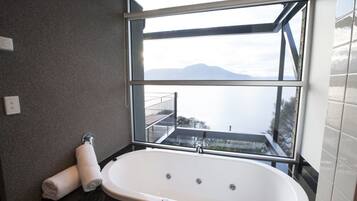 Uma casa de banho moderna com uma banheira grande, uma janela com vista para montanhas e um porta-toalhas.