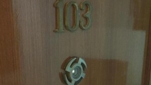 Uma porta de madeira com o número 103 e um puxador circular.