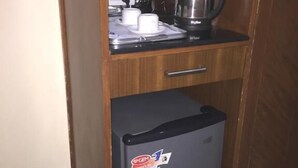 Uma kitchenette compacta com cafeteira, chaleira e pequena geladeira.