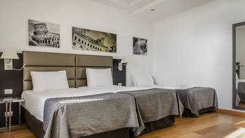 Quarto de hotel com uma cama grande, duas mesas de cabeceira e um espelho. Há três quadros na parede acima da cama.