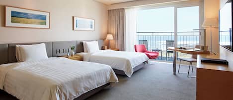Quarto de hotel com duas camas, uma escrivaninha, uma cadeira, uma TV e uma varanda com vista.