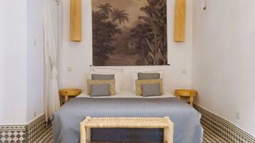 Quarto com cama, almofadas, tapeçaria pendurada e chão xadrez.