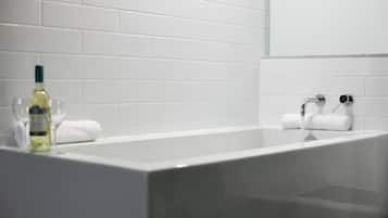Um banheiro moderno com uma banheira branca, dois porta-toalhas e um frasco de loção ao lado.