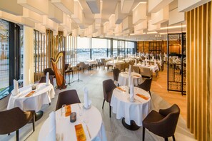Um restaurante moderno com mesas redondas, toalhas de mesa brancas e centros de mesa com velas.