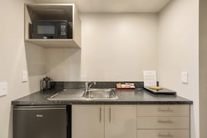 Uma cozinha compacta com micro-ondas integrado, pia de aço inoxidável e lava-louças.