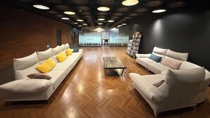 Uma área de estar moderna com dois sofás brancos, uma mesa de centro e uma estante.