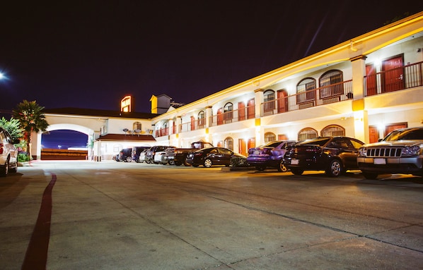 Um hotel com vários andares e uma fileira de carros estacionados em frente.