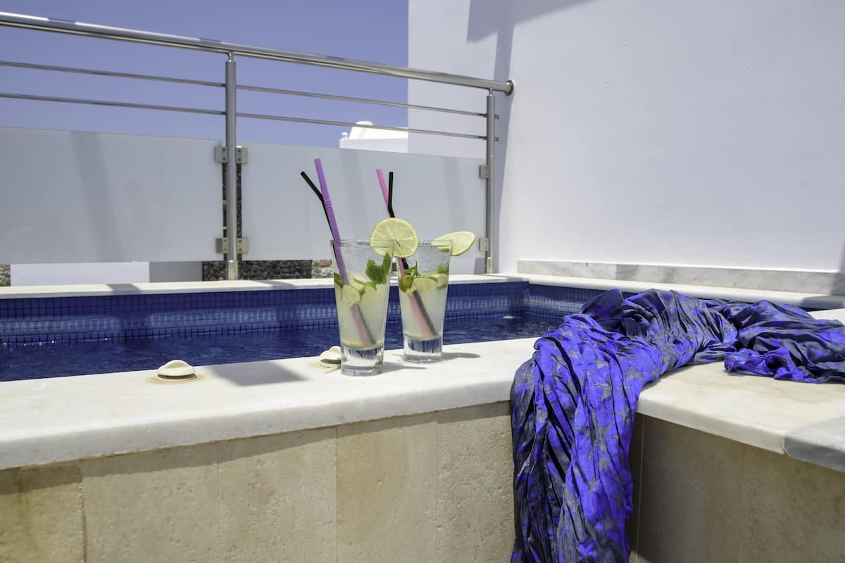 Área da piscina com dois copos de bebida, uma toalha e um corrimão de metal.
