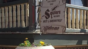 Placa de boas-vindas para Squiers Manor Bed & Breakfast, com um vaso de tulipas vermelhas em primeiro plano.