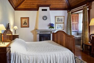 Quarto com cama de madeira, lareira e quadros nas paredes.