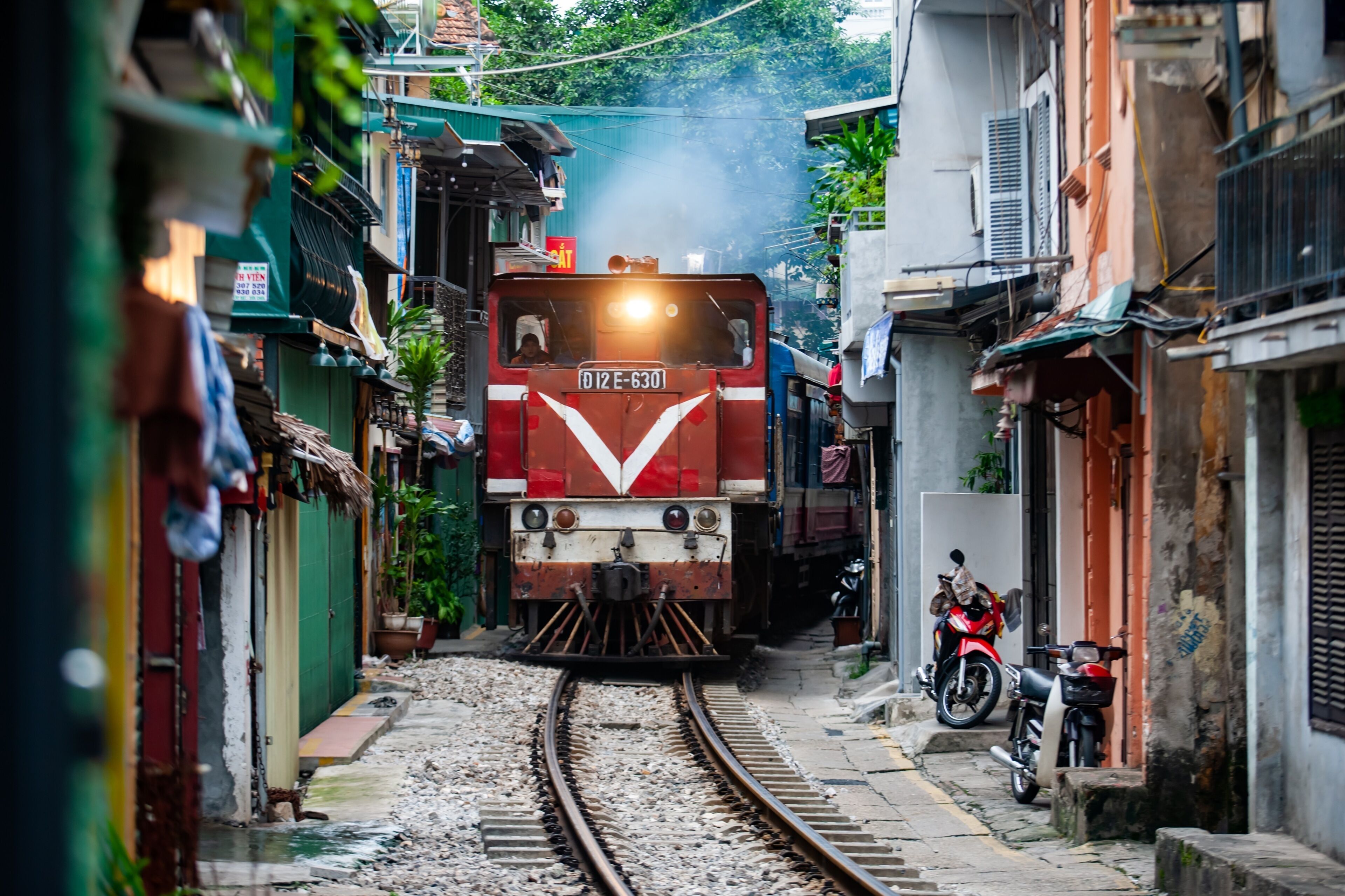 Um trem em trilhos em uma rua estreita, com edifícios de ambos os lados.