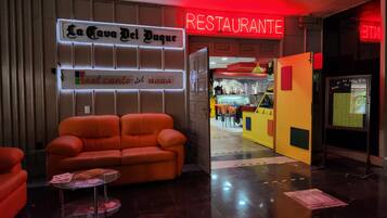Um interior moderno com um letreiro de neon vermelho para 'La Cava Del Duque' e um letreiro 'RESTAURANTE'.