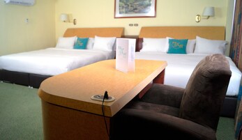 Quarto de hotel com duas camas, uma mesa com um computador portátil e uma cadeira.