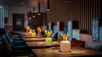 Restaurante com mesas e cadeiras de madeira, cada uma com um pequeno vaso de flores.