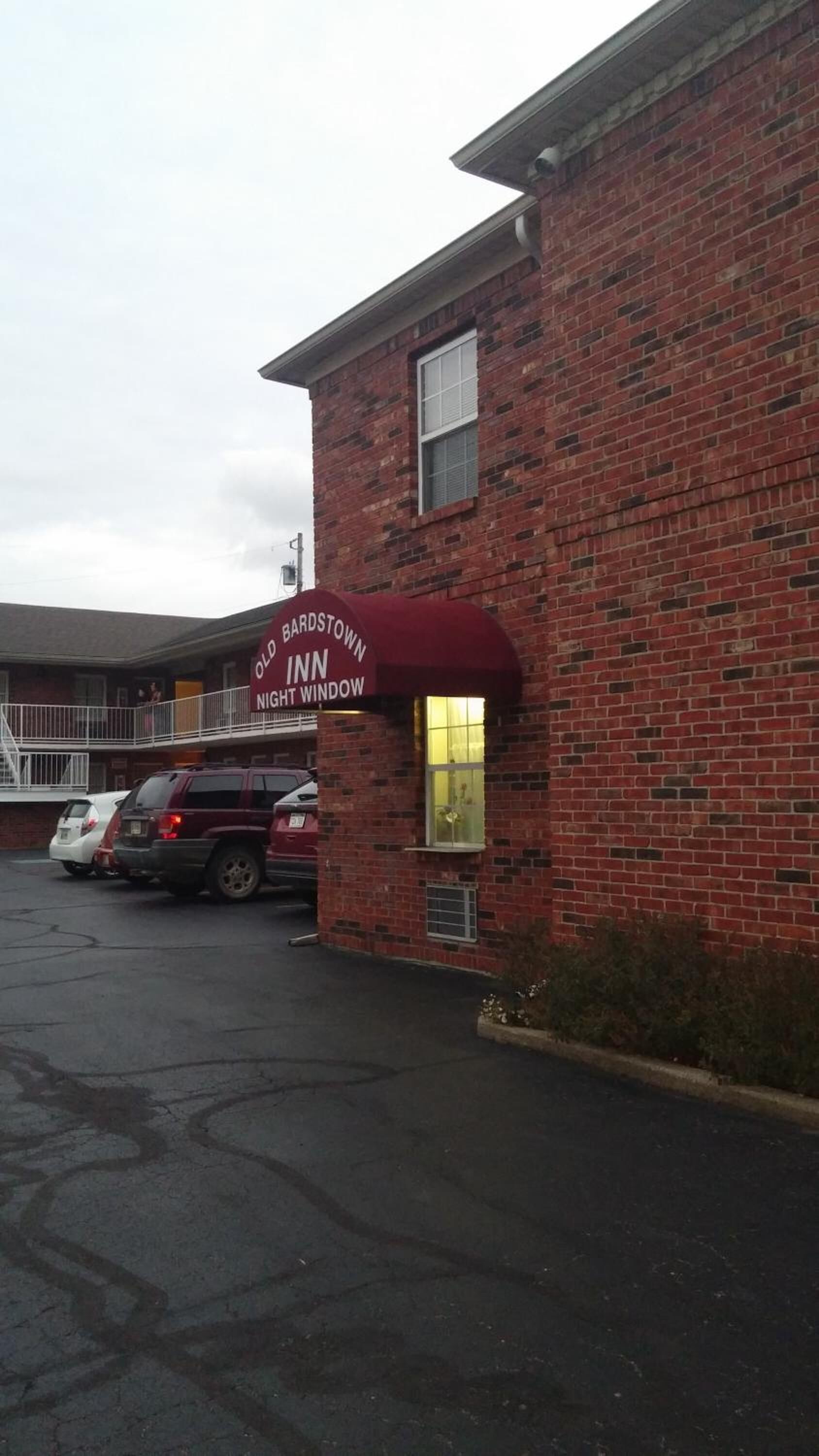 Um edifício de tijolos com toldo vermelho e uma placa que diz 'Old Bardstown Inn Night Window'.