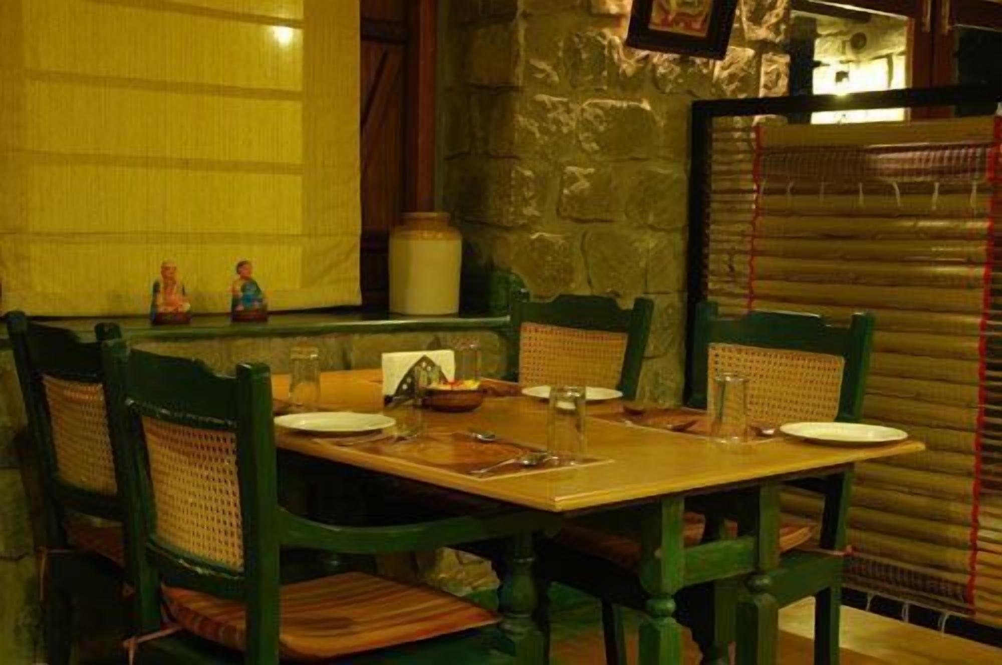Uma sala de jantar com mesa de madeira e cadeiras estofadas em verde.