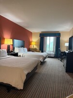 Quarto de hotel com duas camas, uma escrivaninha e uma cadeira.