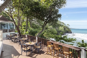 Um terraço com mesas e cadeiras com vista para o litoral.