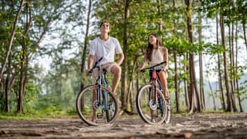 Duas pessoas de bicicleta em uma área arborizada.