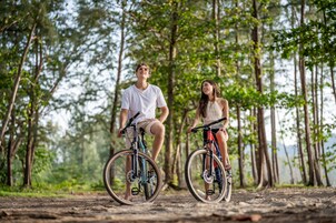 Duas pessoas de bicicleta em uma área arborizada.