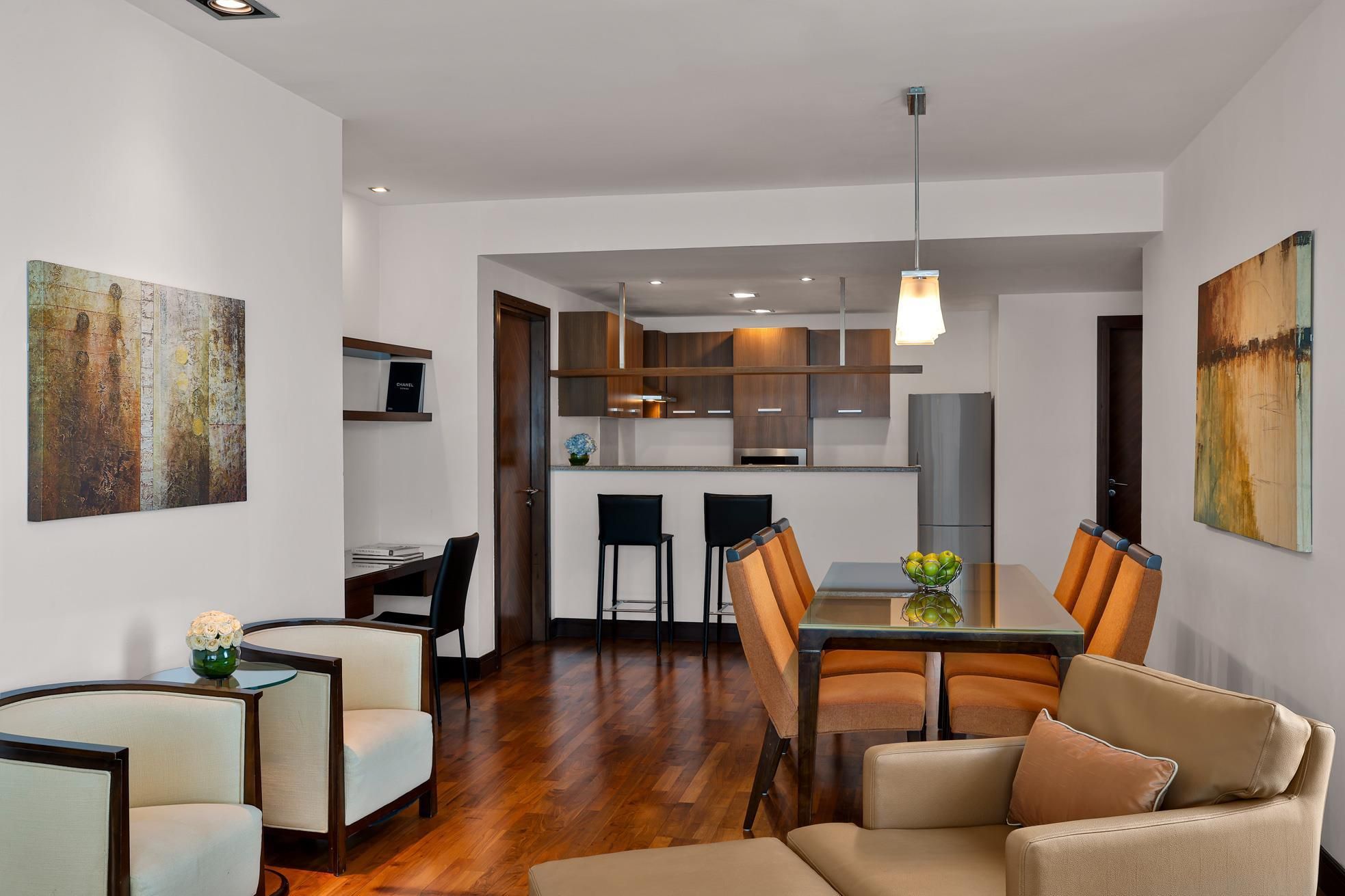 Uma sala de estar moderna com área de jantar, piso de madeira e móveis contemporâneos.