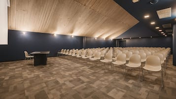 Uma sala de conferência com fileiras de cadeiras, um púlpito e um teto alto com vigas de madeira.