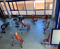 Uma academia com equipamentos de ginástica e cadeiras vermelhas.