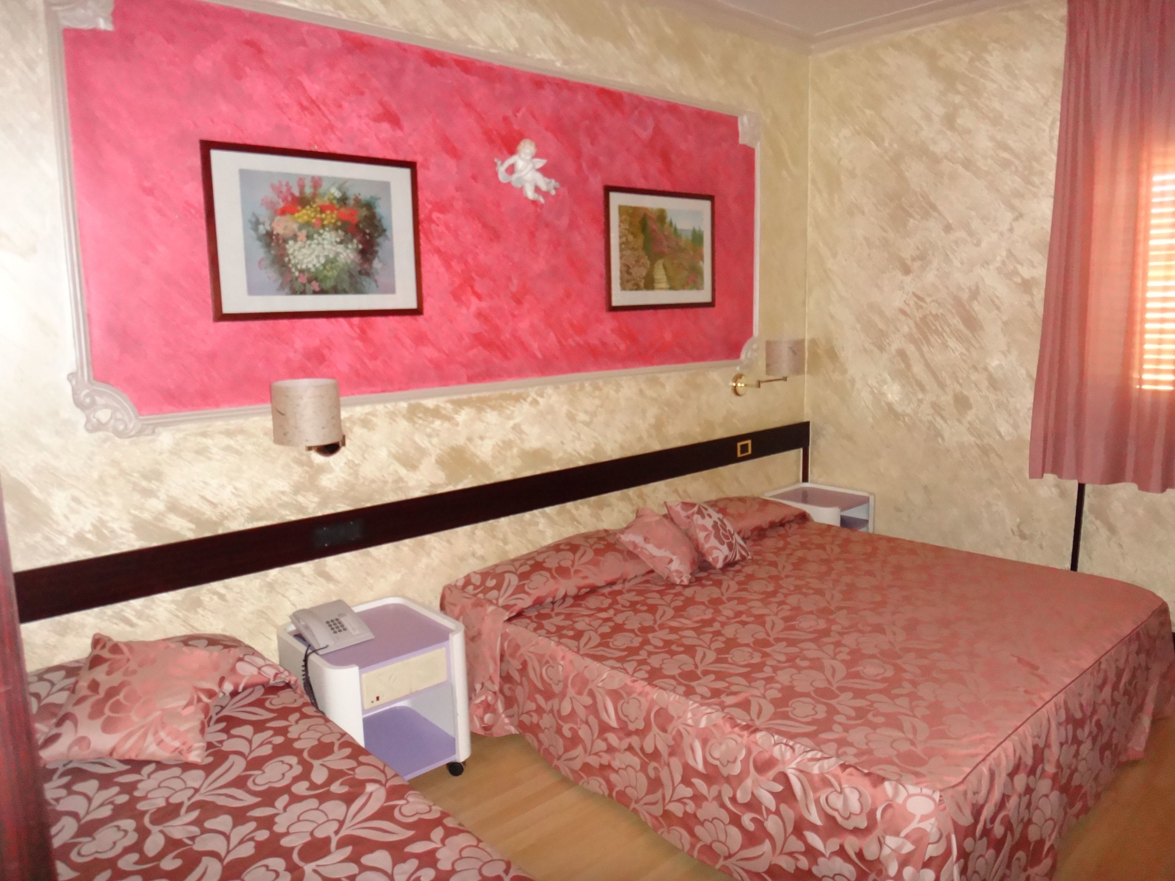 Quarto com duas camas, uma mesa de cabeceira e um telefone fixado na parede.
