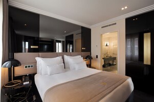 Quarto de hotel com uma cama grande, abajures, telefone e espelho.
