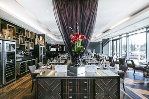 Restaurante moderno com área de bar central, prateleiras de vinho e diferentes opções de assentos.