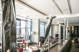 Um interior moderno com divisória de vidro, mobiliário de metal e iluminação pendente.