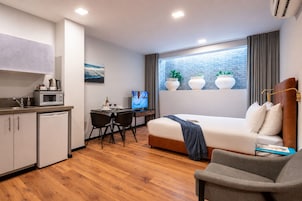 Quarto de hotel moderno com cozinha compacta, sala de jantar, cama com vista e área de estar.