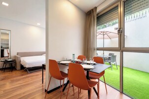 Quarto de hotel com área de refeições, uma cama e vista para um gramado verde.