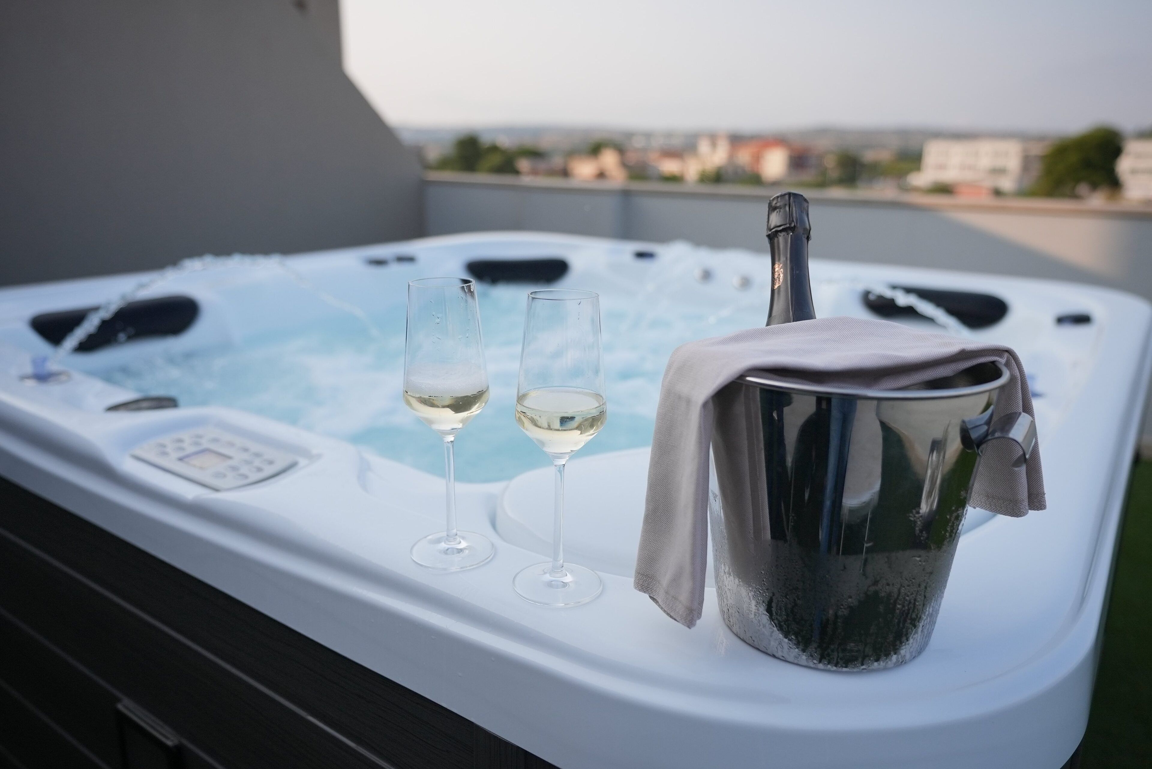 Uma banheira de hidromassagem com duas taças de vinho branco e um balde de gelo.