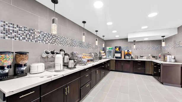 Uma cozinha moderna com um balcão extenso, diversos eletrodomésticos e painel de azulejos.