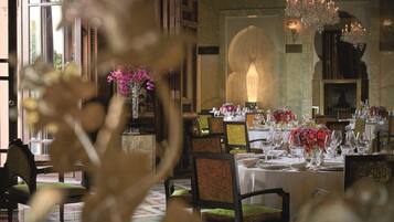 Um restaurante com mesas postas para refeições, com centros de mesa florais e elegantes louças.