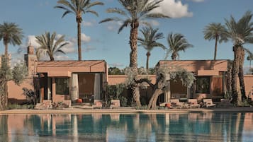 Um resort com piscina, palmeiras e um edifício com torre.