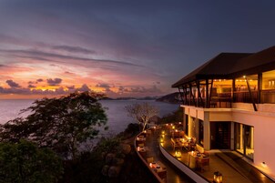 Um imóvel à beira-mar com área de refeições com vista para o mar, apresentando assentos externos e uma vista do pôr do sol.